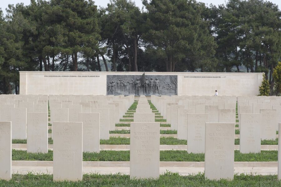 Military cemetery with aligned tombstones memorial wall and trees at Gallipoli