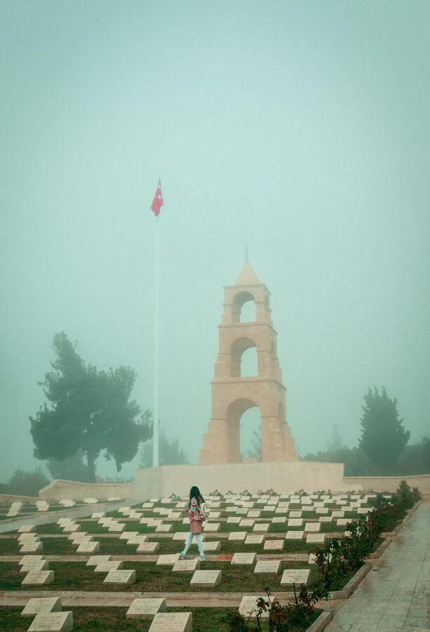 Girl walking among graves at misty Canakkale Martyrs Memorial