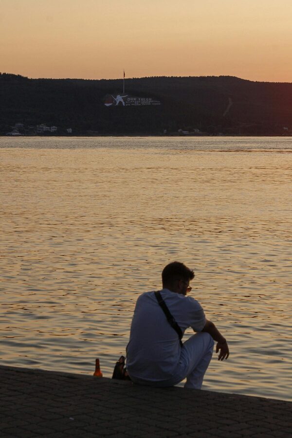 Man sitting by the Dardanelles Strait in Canakkale watching sunset