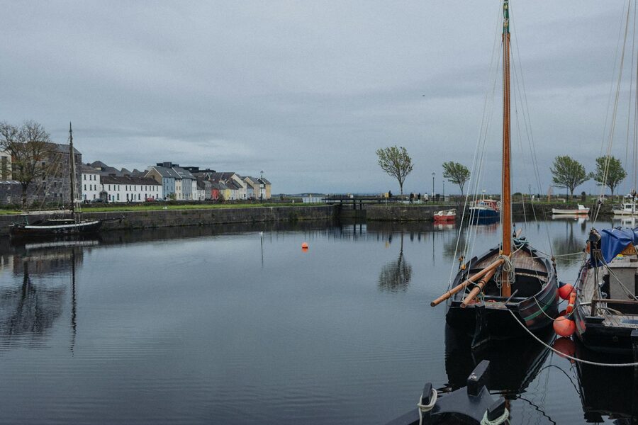 Sailboats moored in Galway harbour with historic buildings