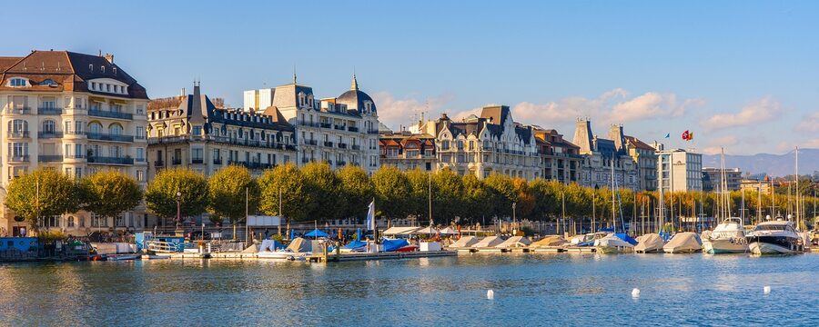 Boats moored in Geneva port with historic buildings and waterfront behind them