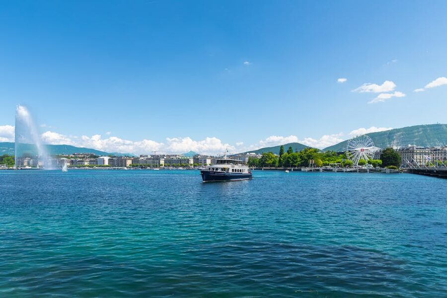 Lake Geneva with the Jet d'Eau fountain and a Ferris wheel under blue skies
