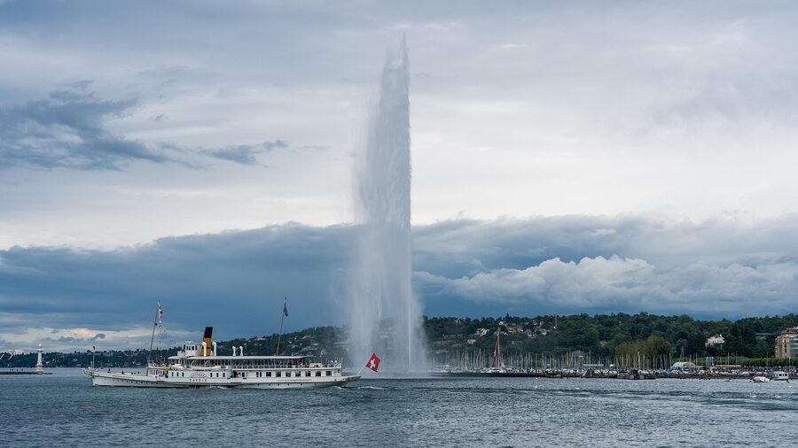 Jet d'Eau fountain at sunset with warm golden light reflecting on Lake Geneva