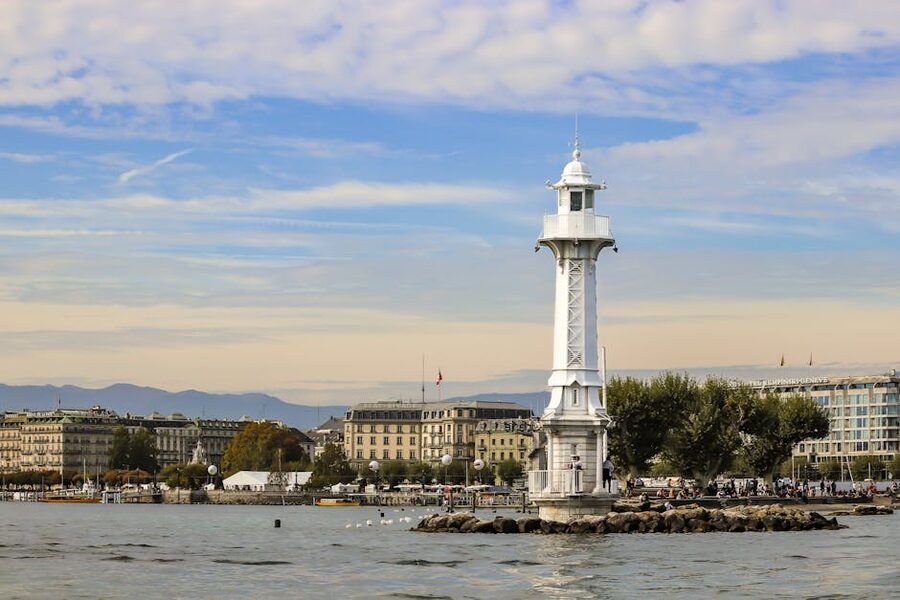 Lighthouse on Lake Geneva with the city skyline in the background under evening light