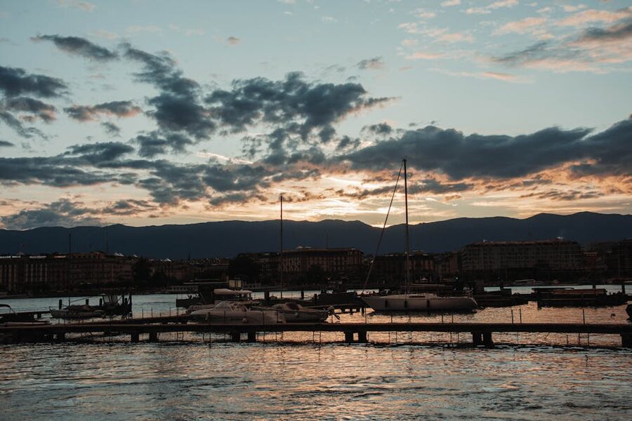 Yachts moored at sunset on Lake Geneva with city lights reflecting on the water