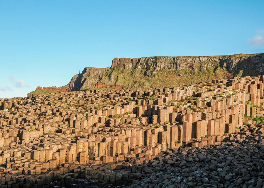 Hexagonal basalt columns at the Giants Causeway with cliffs behind