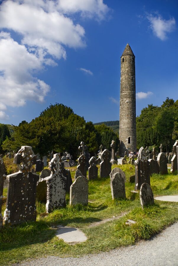 Ancient round tower and gravestones at Glendalough monastic site Ireland