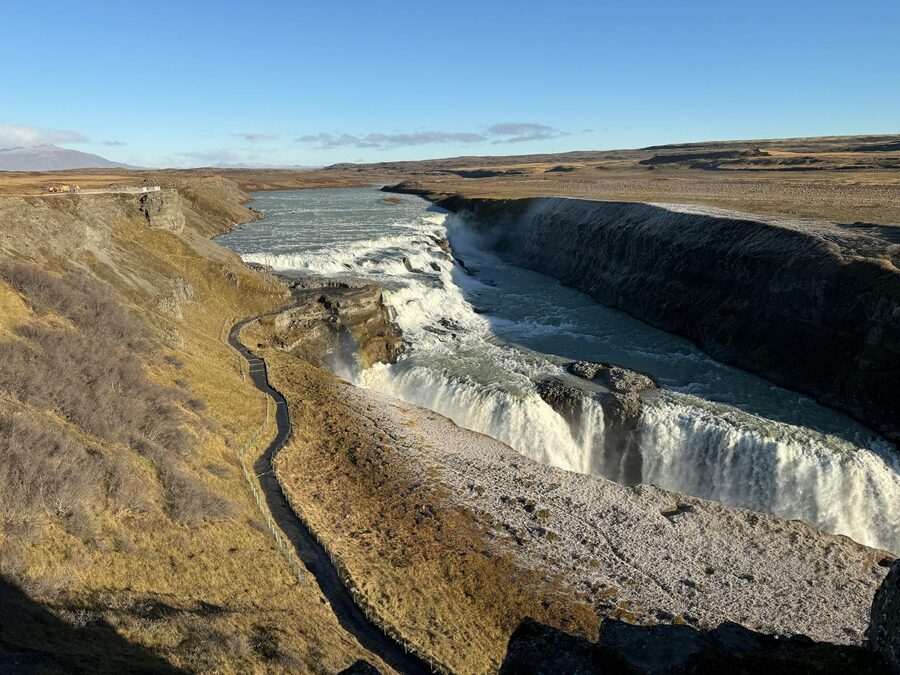 Gullfoss waterfall flowing between green cliffs on a clear summer day in Iceland