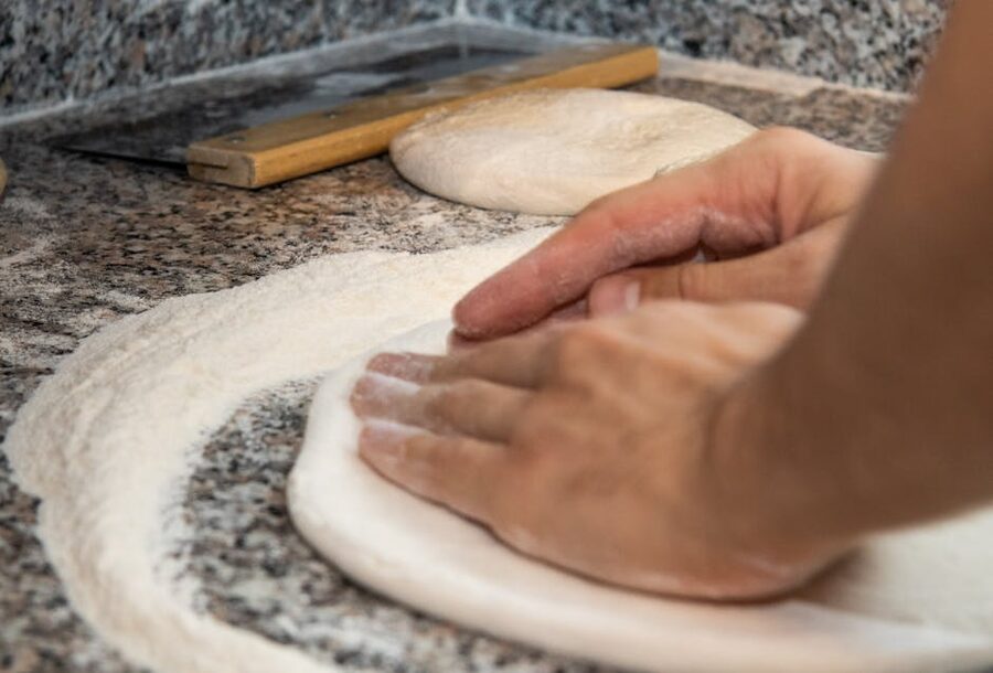 Hands kneading dough on floured surface