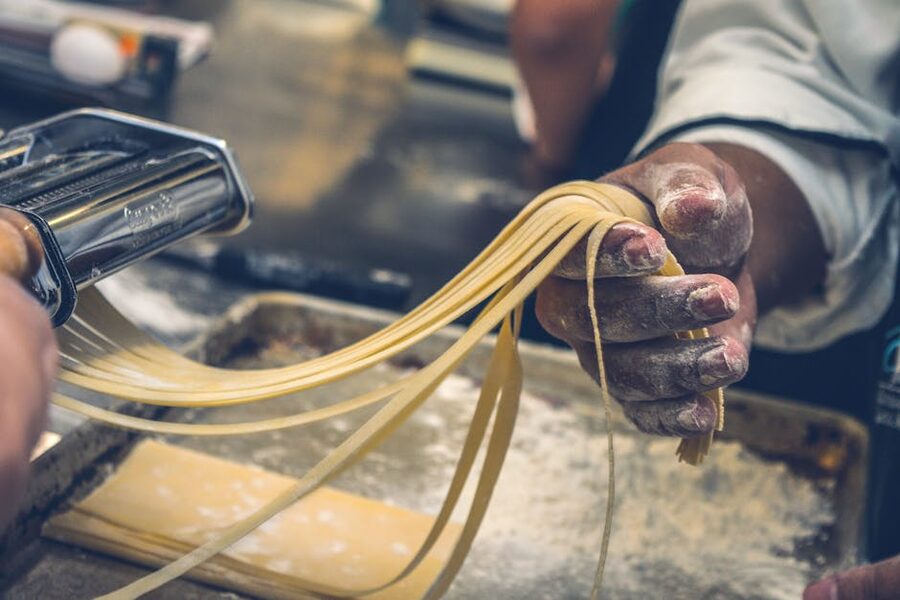 Hands making fresh pasta from scratch