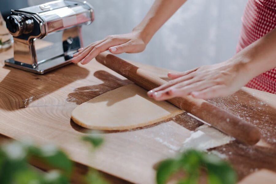 Hands rolling dough on wooden board