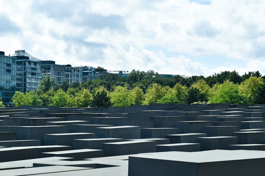 Wide view of the Holocaust Memorial in Berlin with trees and cloudy sky