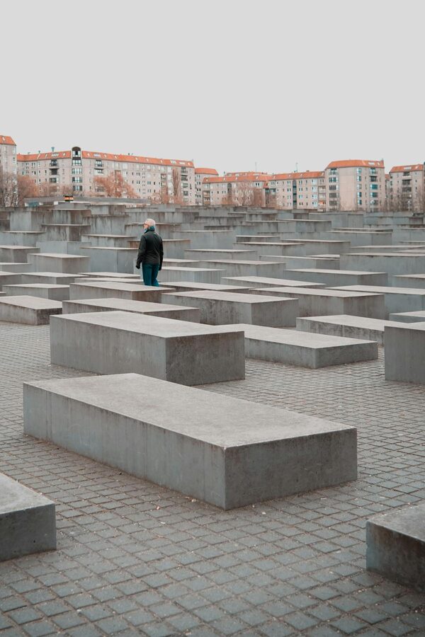 Solitary person walking between tall stelae at Berlin's Holocaust Memorial