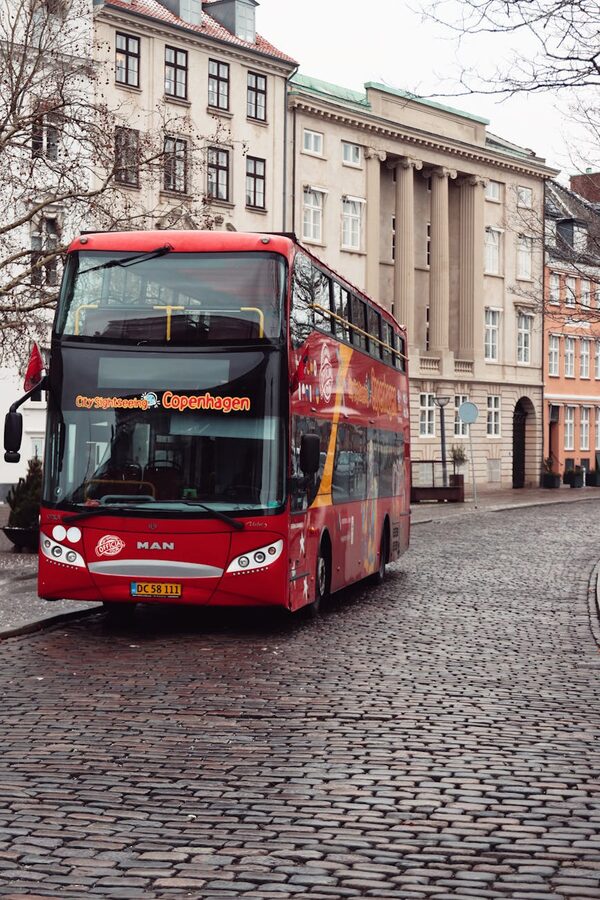 Red double-decker hop-on-hop-off tour bus on a historic Copenhagen street