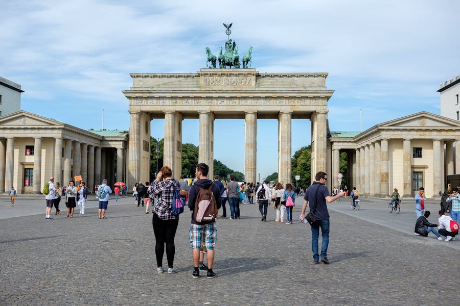Visitors walking through the Brandenburg Gate in Berlin on a sunny day
