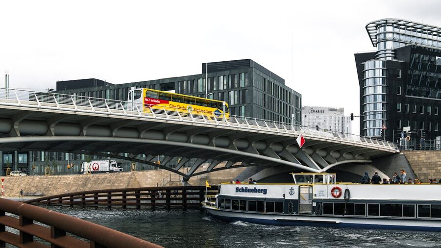 Berlin bridge with modern architecture and boat passing underneath