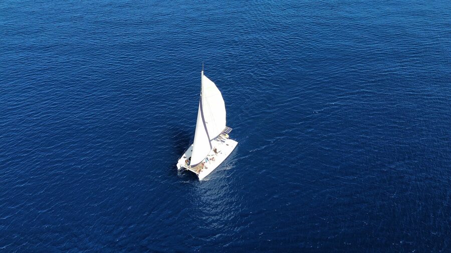 Aerial view of sailboat in deep blue ocean