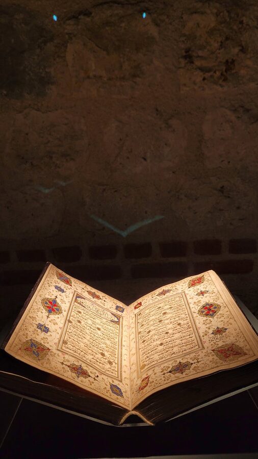 Ancient illuminated manuscript displayed under focused lighting in a museum