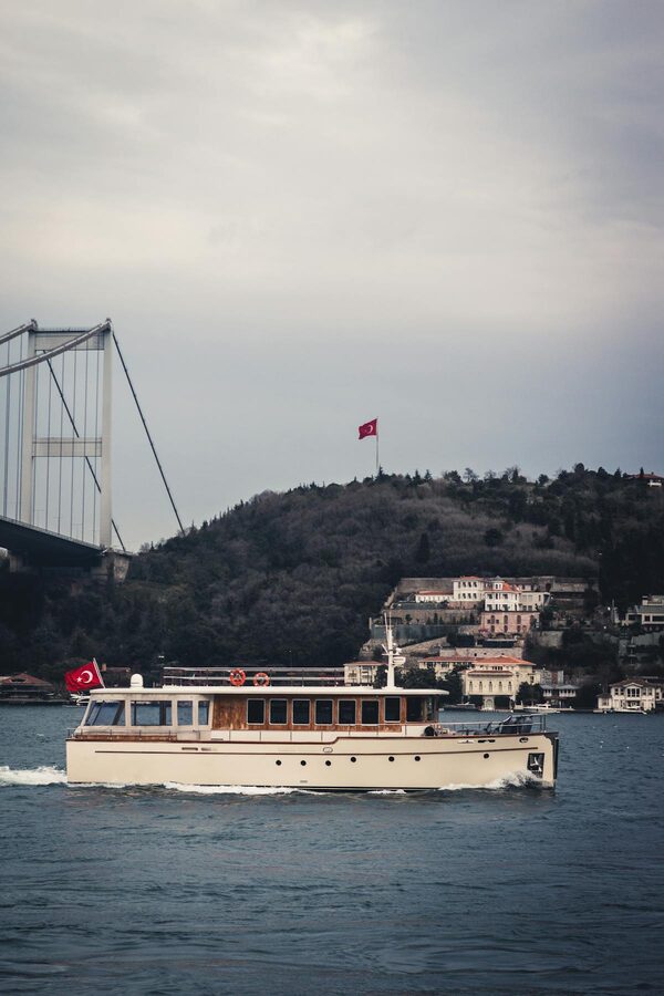 Tourist boat on the Bosphorus with Turkish flag and bridge in Istanbul