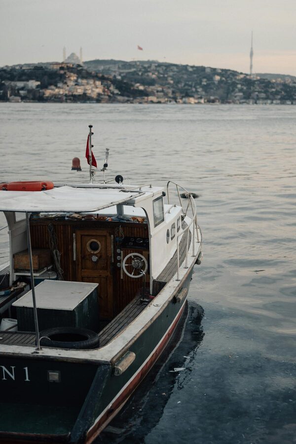 Vintage wooden boat on the Bosphorus with Istanbul skyline at sunset