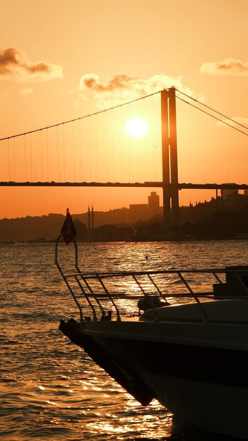 Bosphorus Bridge silhouette at sunset with boat