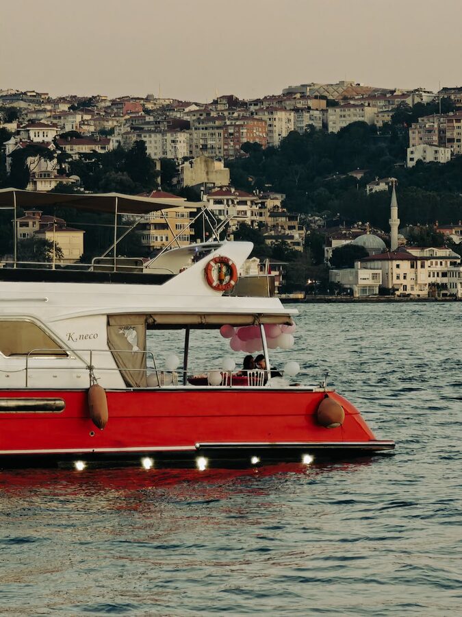 Red yacht cruising the Bosphorus with Istanbul cityscape