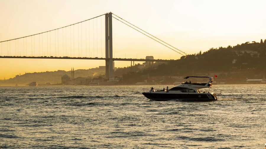 Yacht sailing toward bridge at sunset in Istanbul