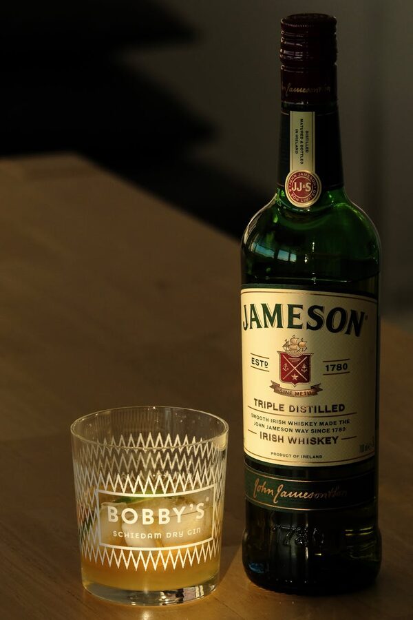Jameson Irish whiskey bottle and glass on wooden table under warm lighting