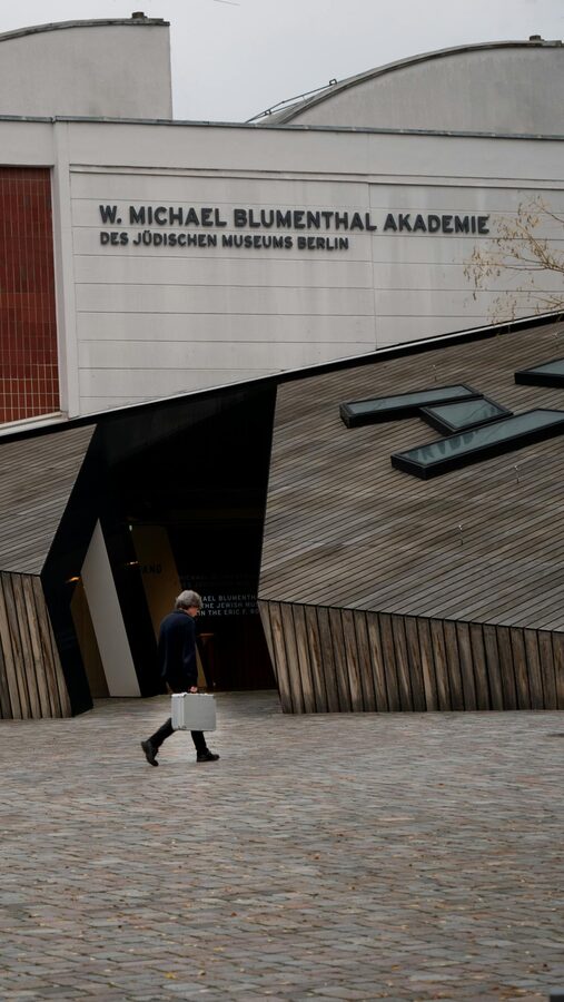 Person walking past the zinc-clad exterior of the Jewish Museum Berlin
