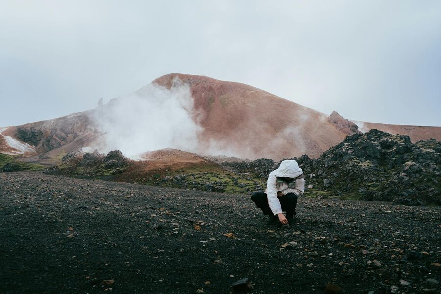 Solo hiker walking across geothermal terrain in Iceland highlands