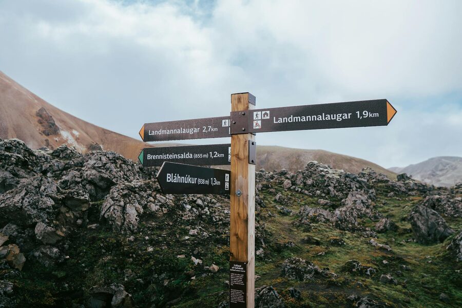 Hiking trail signposts in Landmannalaugar with mountains in the background