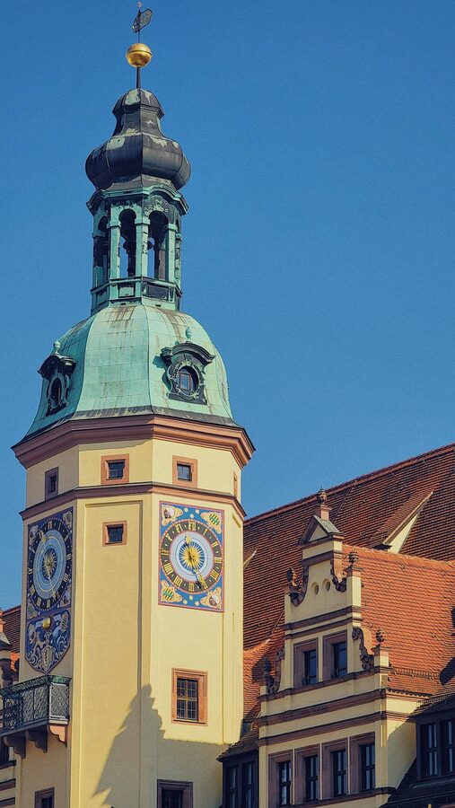 Historic bell tower in Leipzig under clear blue sky with ornate stonework