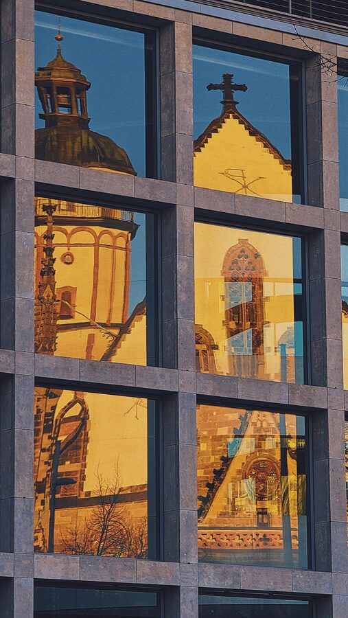 St Thomas Church Leipzig reflected in modern glass building facade at sunset