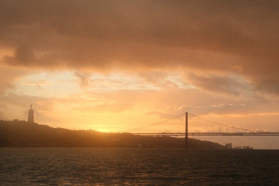Lisbon 25 de Abril Bridge and Cristo Rei statue over Tagus River at sunset