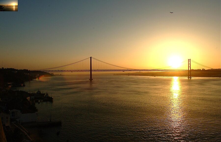Ponte 25 de Abril bridge in Lisbon glowing orange at sunset