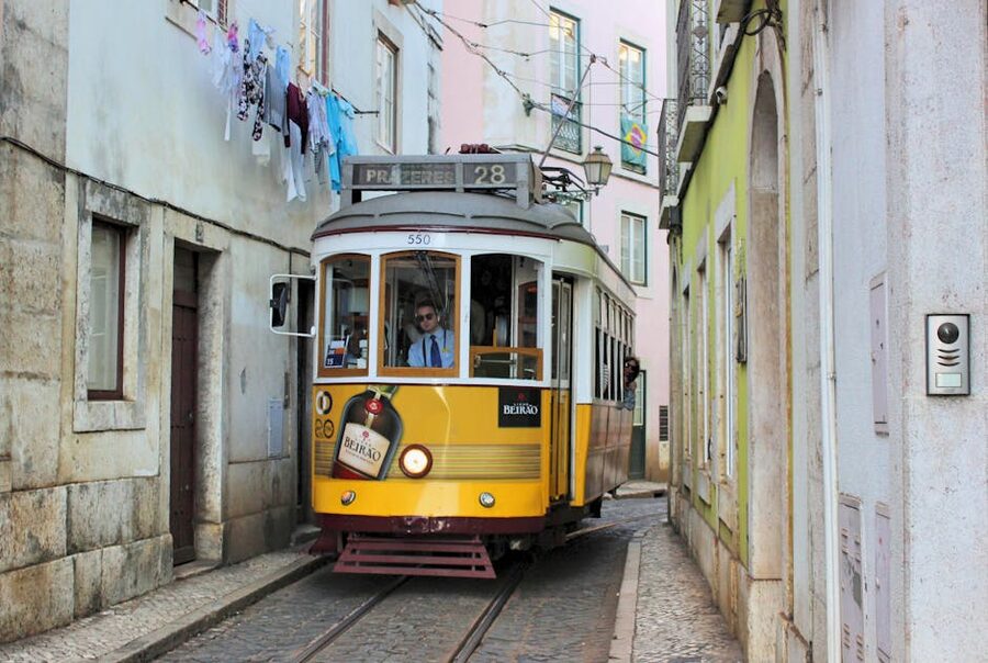 Tram 28 navigating a narrow cobblestone street in Lisbon
