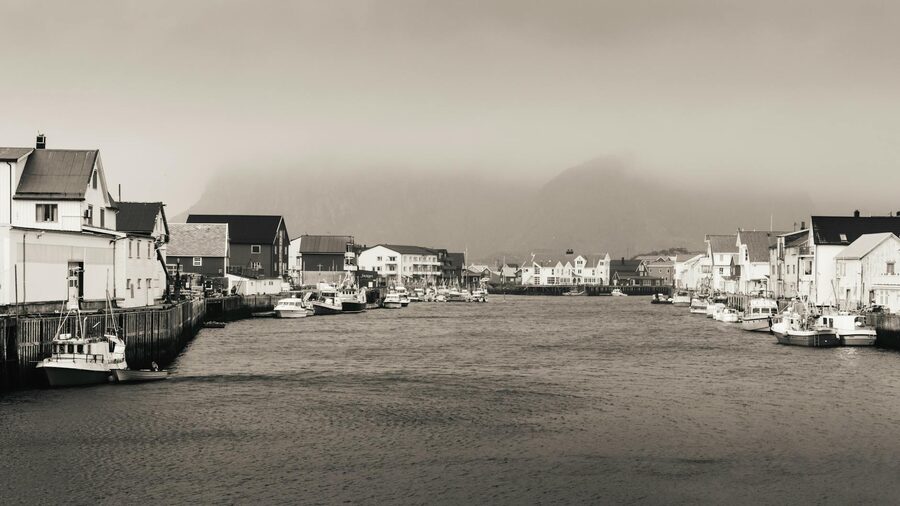 Henningsvær marina on a foggy day with boats and mountain reflections