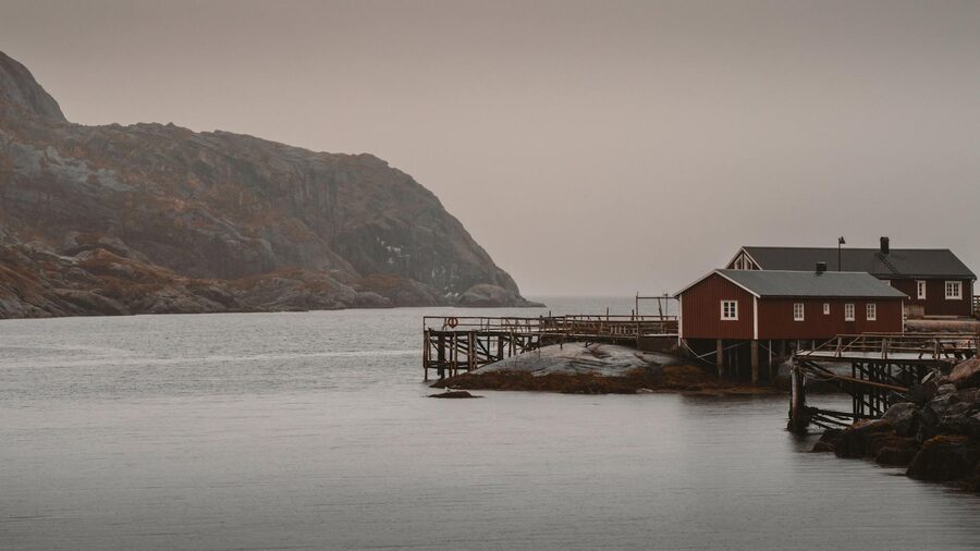Red wooden houses on stilts over the water in Lofoten