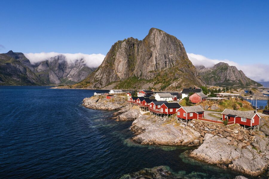 Aerial view of Reine village with red houses and dramatic mountain cliffs