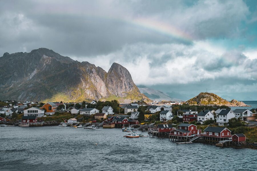 Reine village with red cabins and a rainbow arcing over the mountains