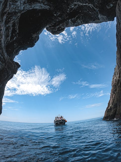 A boat approaching a sea cave opening in bright blue water off Malta's coast