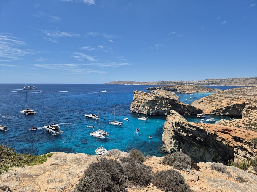 Comino island coastline with boats anchored in bright blue water
