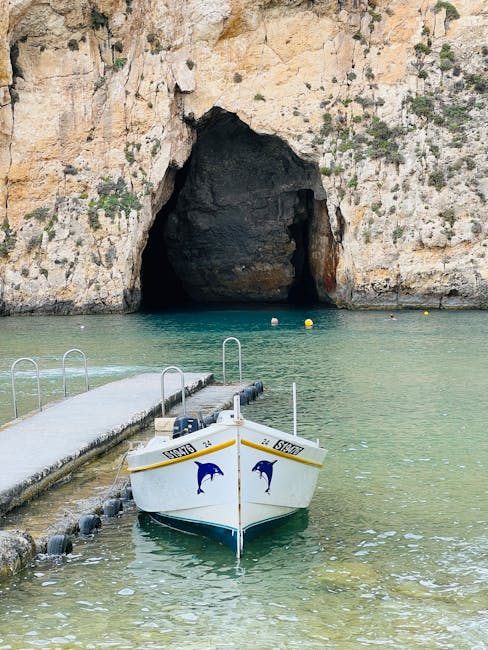 A boat moored near a natural grotto entrance in Malta with blue water
