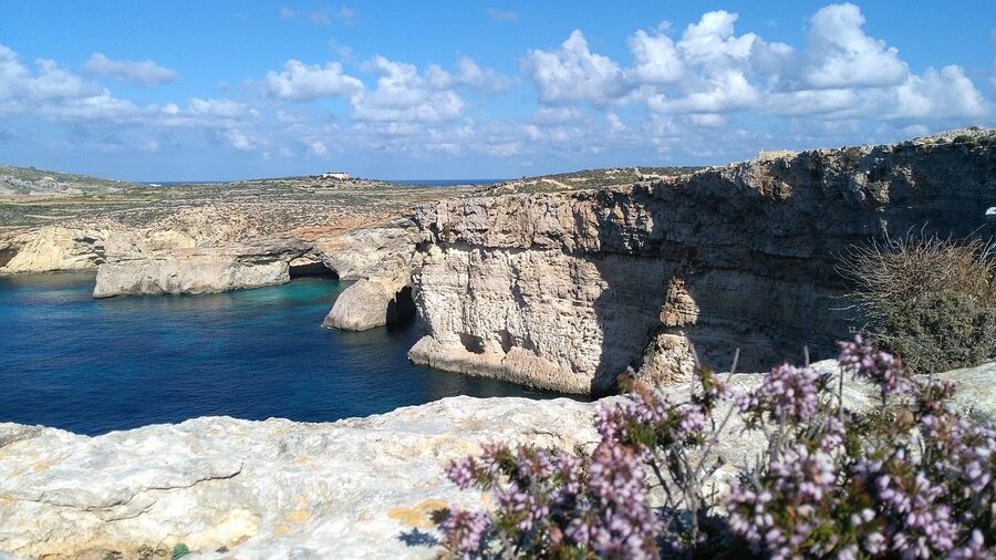 Limestone cliffs and a lagoon along Malta's coast with deep blue water below