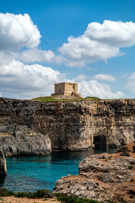 Malta's limestone coastline with azure water and a historic watchtower on the cliff