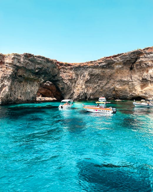 Boats near a natural stone arch and rock formation in turquoise Mediterranean water