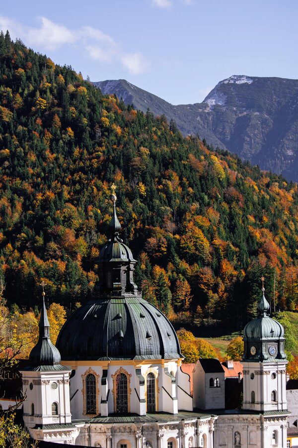 Ettal Abbey surrounded by autumn foliage set against the Bavarian Alps