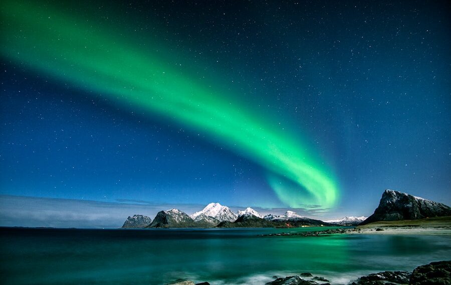 Green aurora borealis over mountain peaks