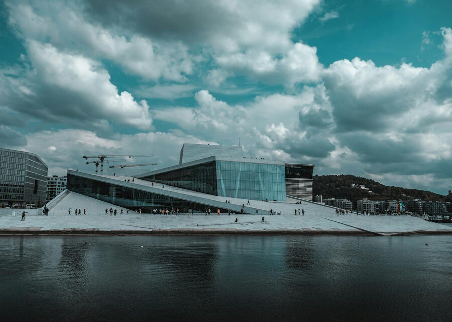 Oslo Opera House with dramatic clouds and waterfront reflections