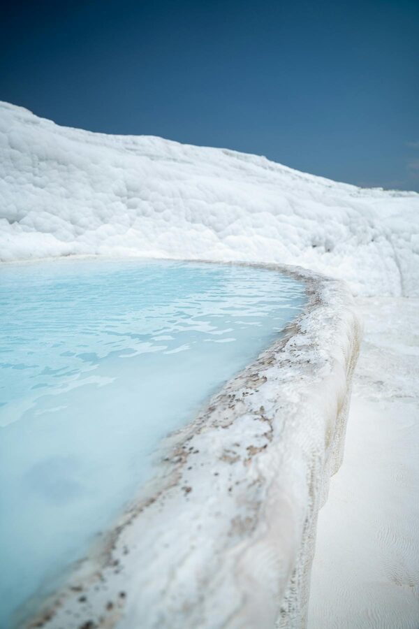 Crystal clear thermal water in a white travertine pool at Pamukkale